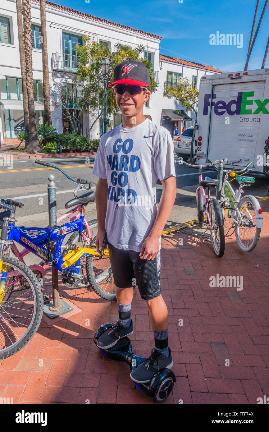 A male teenager stops and pauses his ride on his hoverboard on a ...