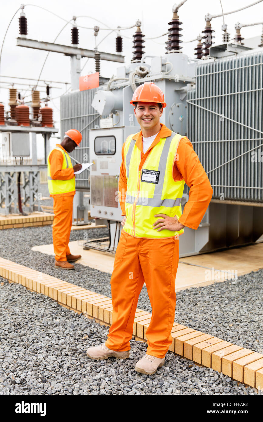 happy electrical engineer in substation with colleague on background ...
