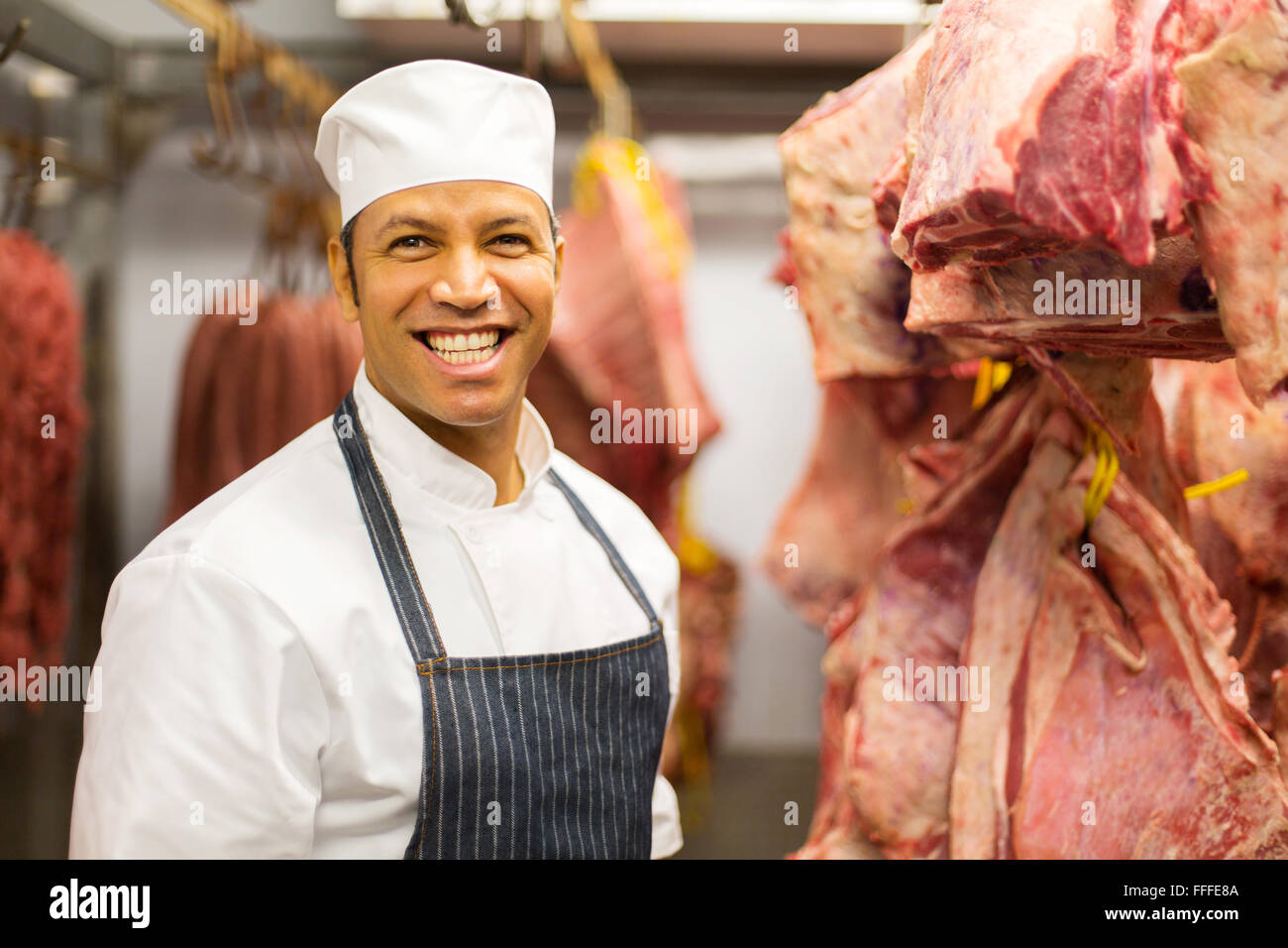 happy butcher standing in cold room with beef hanging Stock Photo - Alamy