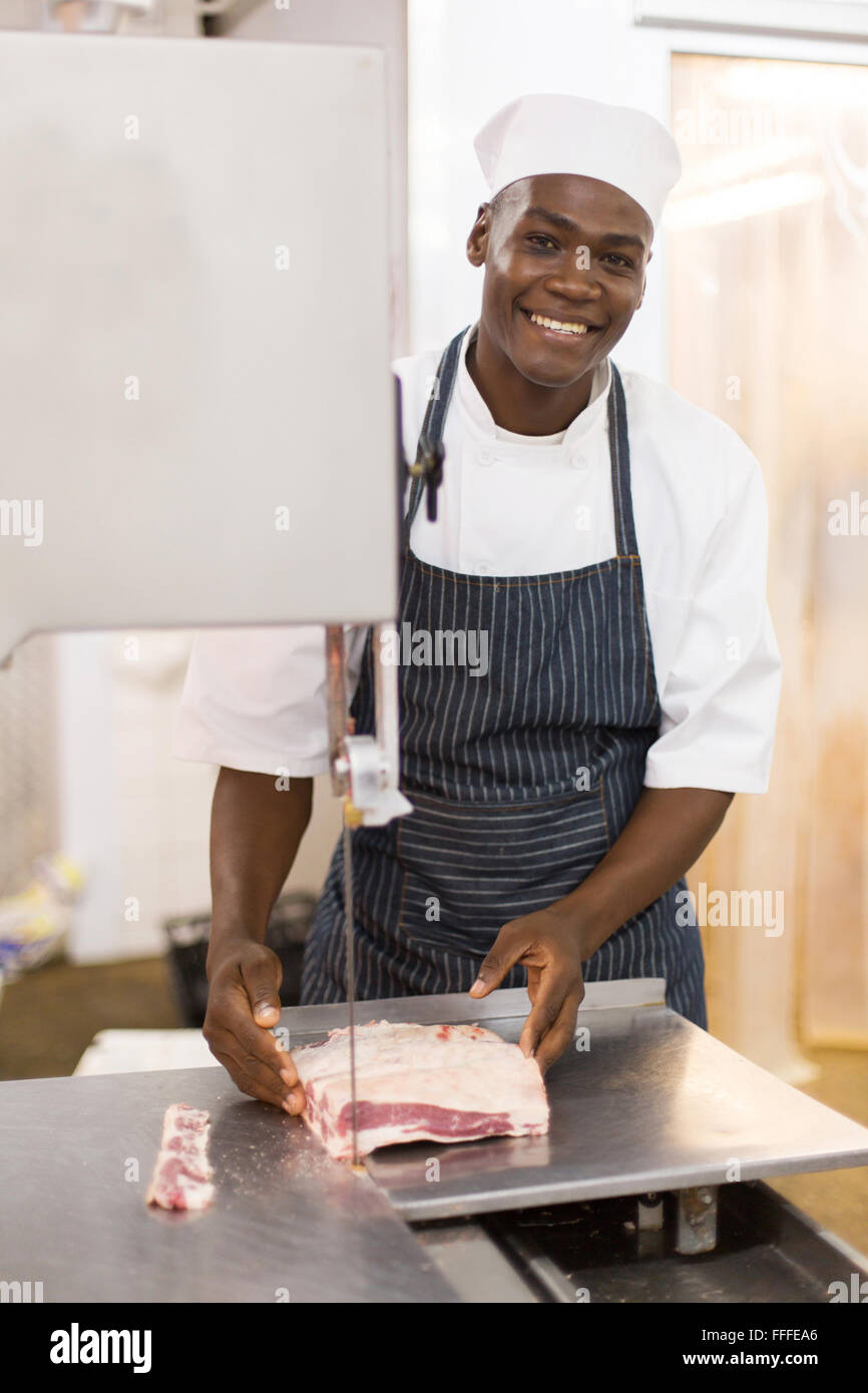 happy young African male butcher cutting meat on bandsaw Stock Photo ...