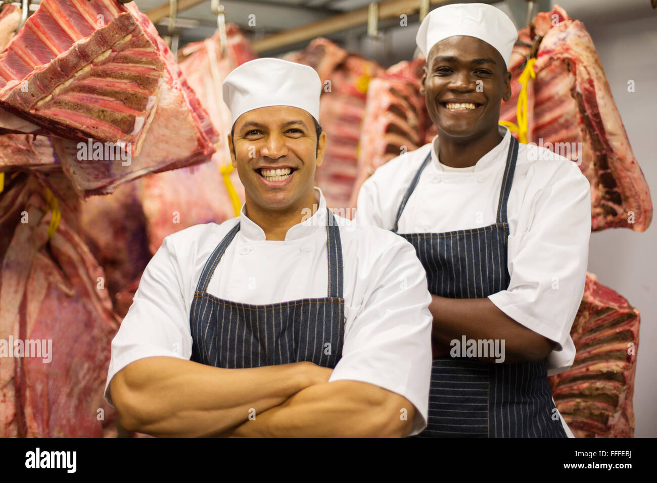 portrait of happy male butchers standing in front of raw meat Stock ...
