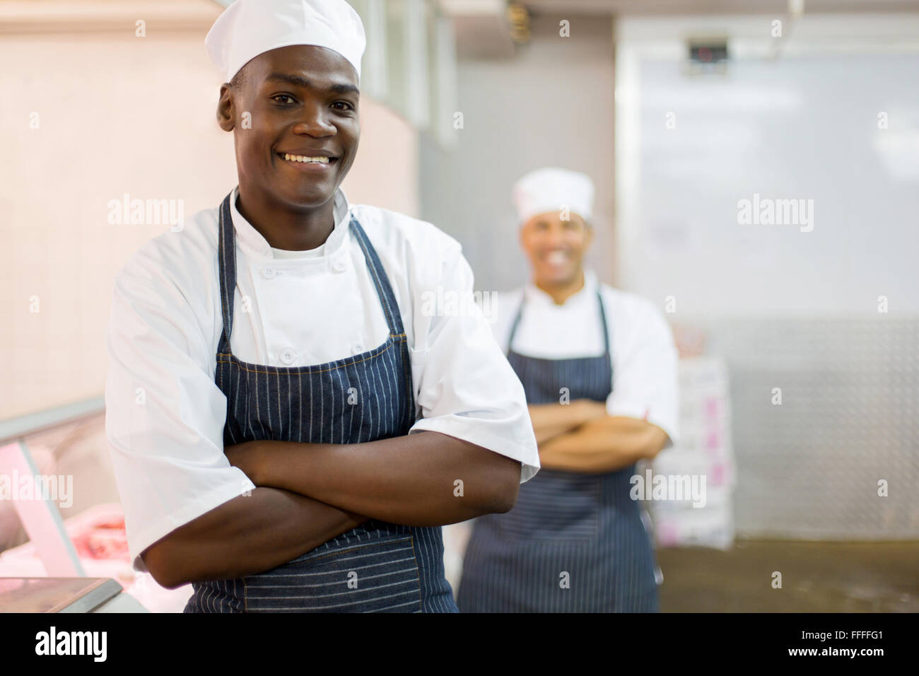 portrait of smiling African American butcher with colleague on ...