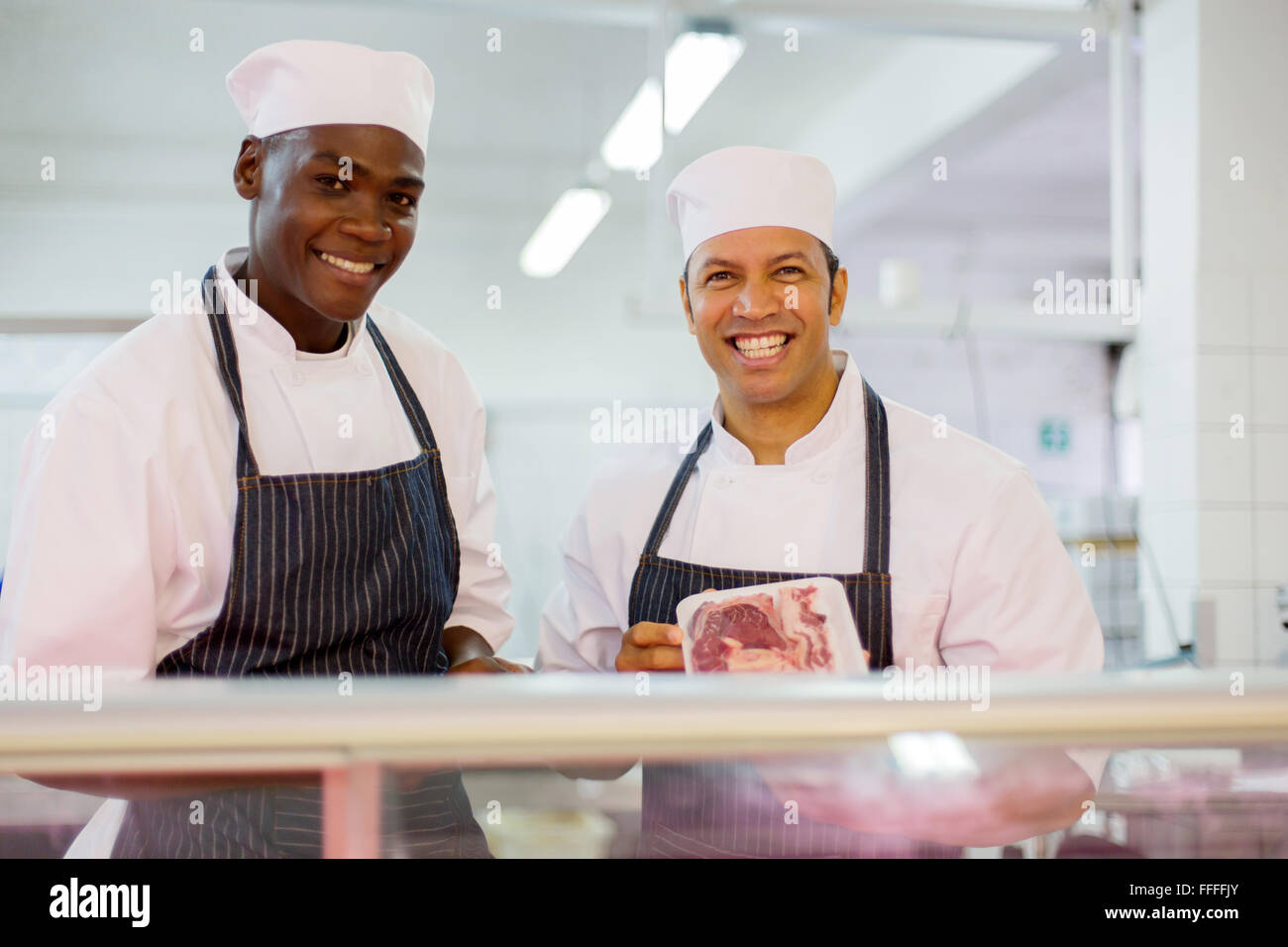 portrait of happy male butchers standing at butchery counter Stock ...
