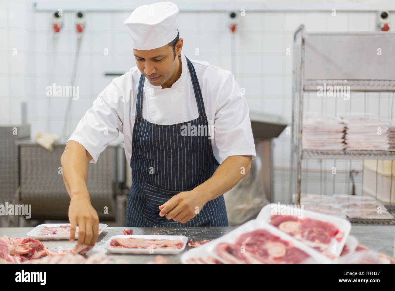 confident mid age butcher packing meat pieces in butchery Stock Photo ...