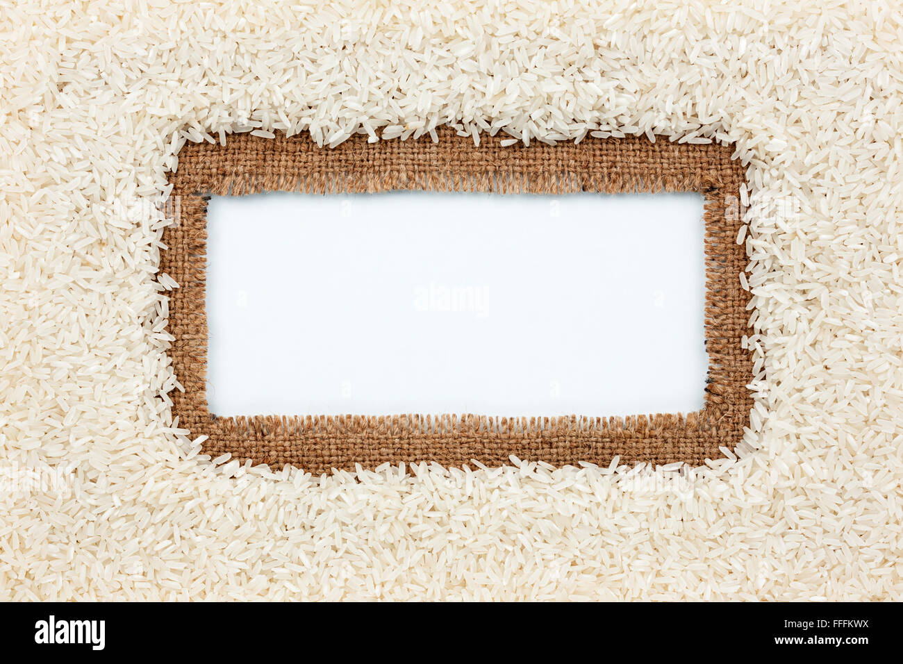 Frame made of burlap and rice grains lies on white background, with ...