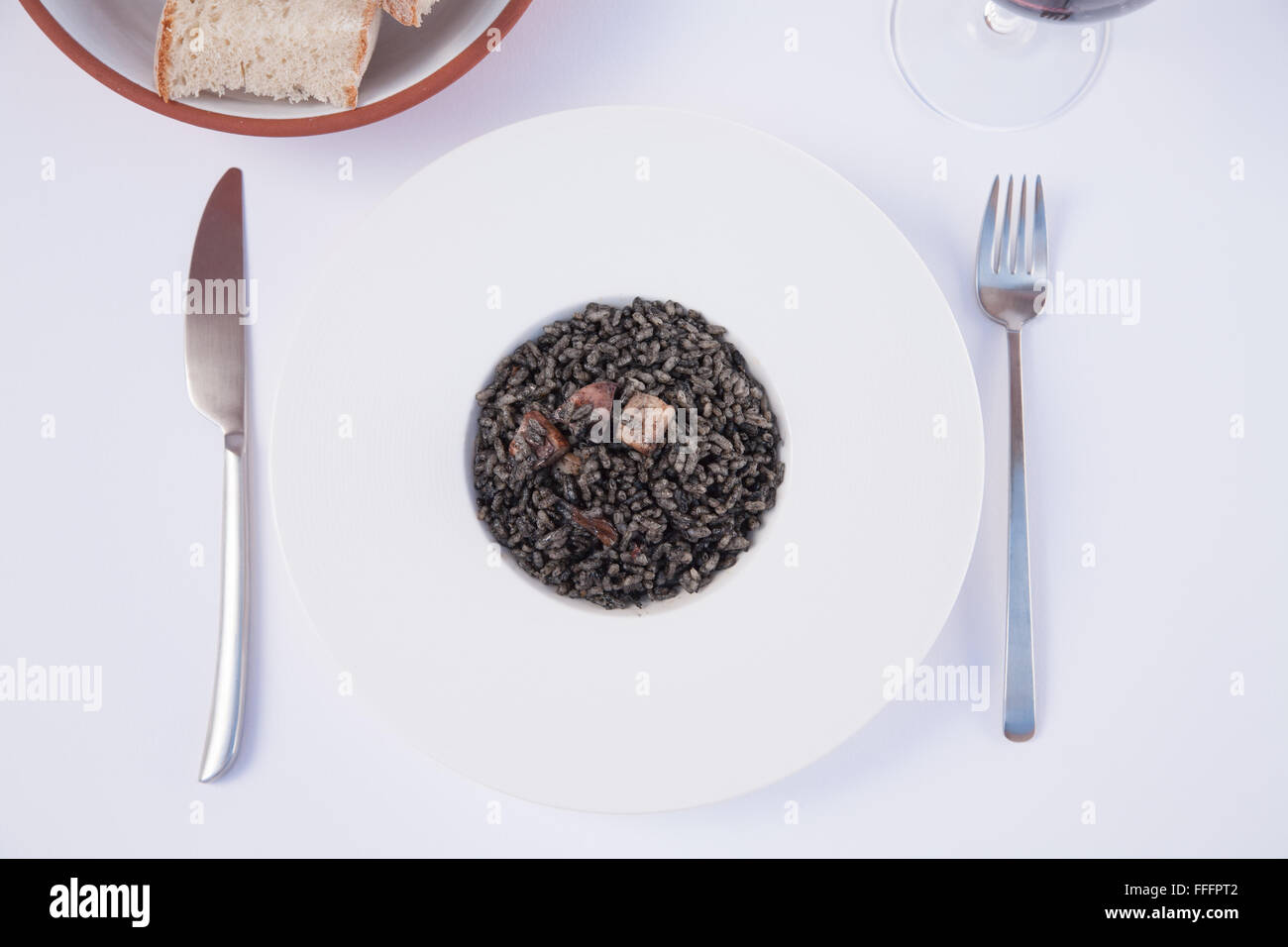 top aerial view of white circular plate with black ink squid rice dish ...