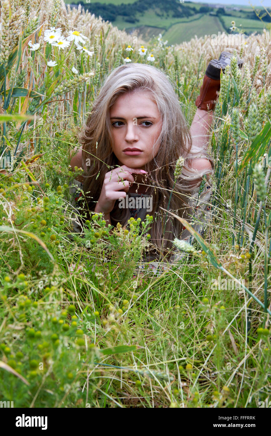Beautiful teenage girl lying in a field thinking Stock Photo - Alamy