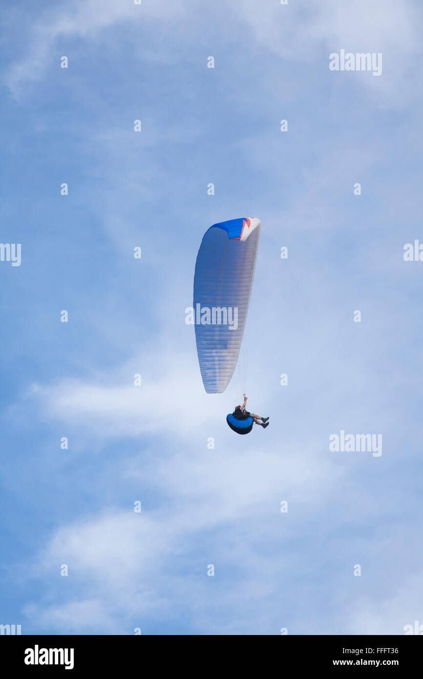 black paraglider flying in cloudy white and blue sky Stock Photo - Alamy