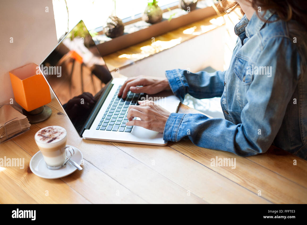 woman with blue jeans jacket typing on keyboard pc laptop next to ...