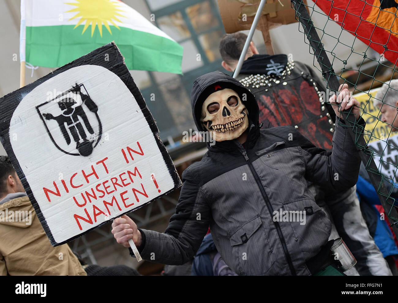 Munich, Germany. 13th Feb, 2016. A man in a skull mask holds up a sign ...