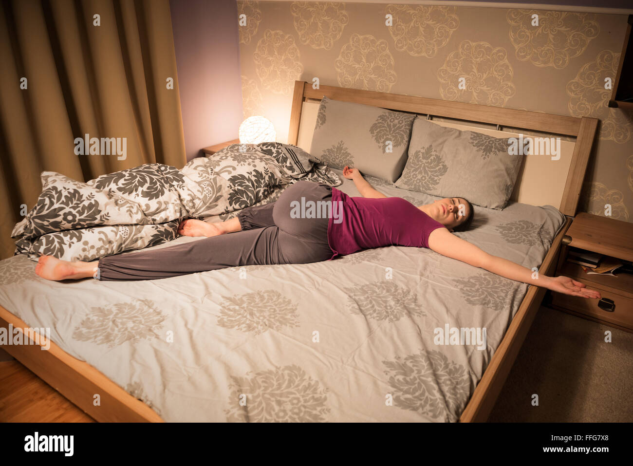 Young woman doing the Reclining Spinal Twist yoga pose before going to ...