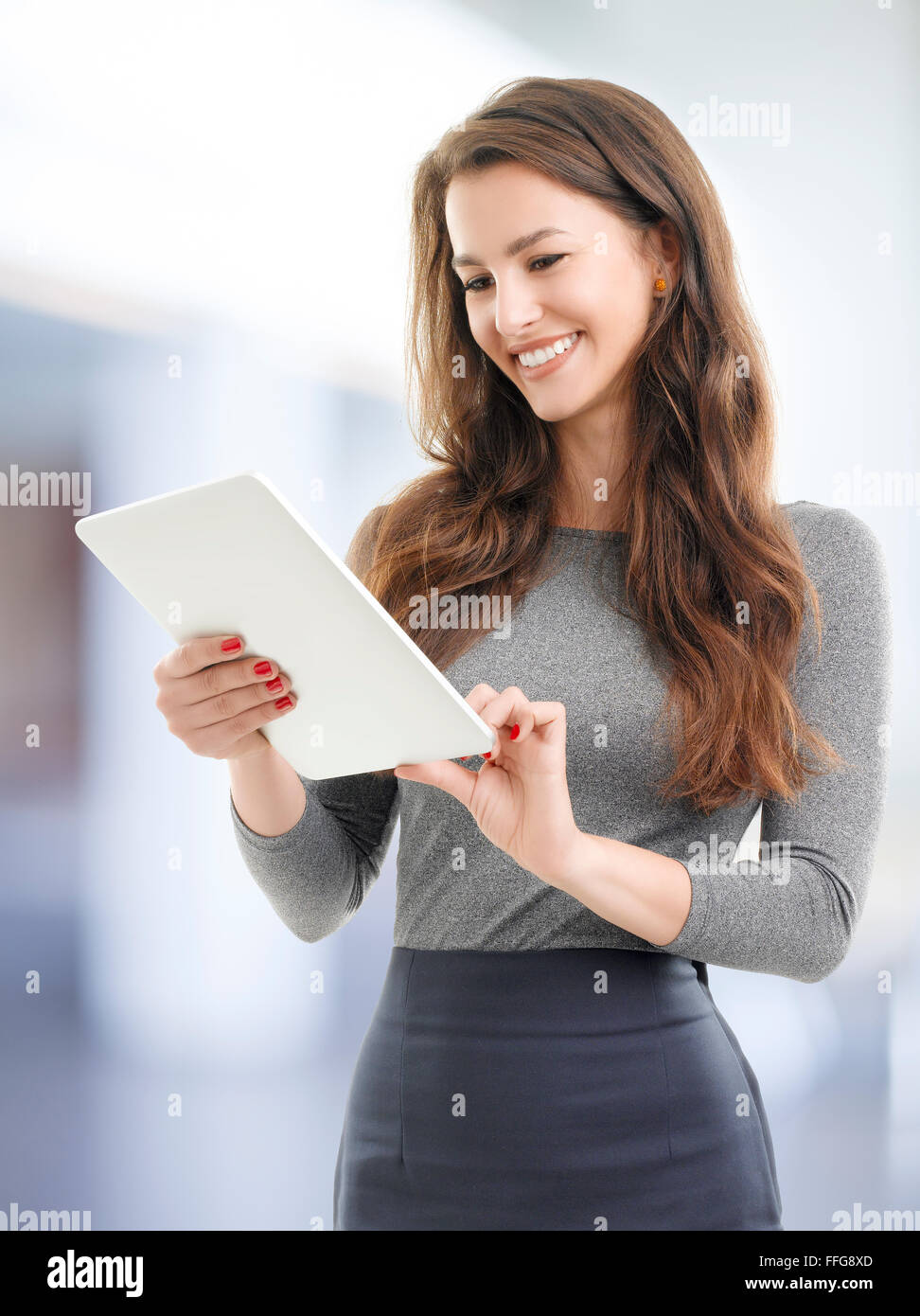 Image of beautiful young woman standing while holding digital tablet in ...