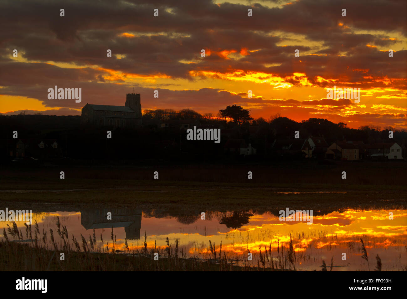 Salthouse Village church and flooded marshes in foreground at sunset ...