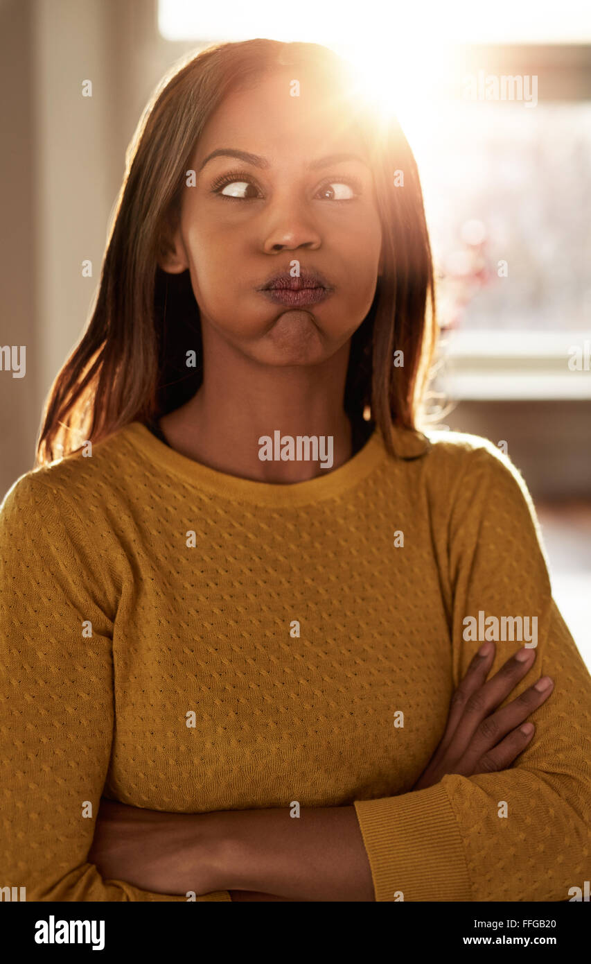 Young woman making a goofy face squinting and puffing out her cheeks in ...