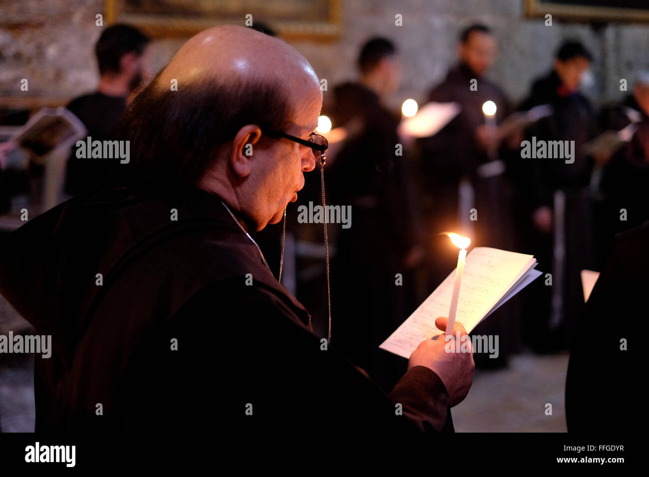 Christian Latin Catholic priest holds a candle and a hymnal book as he ...