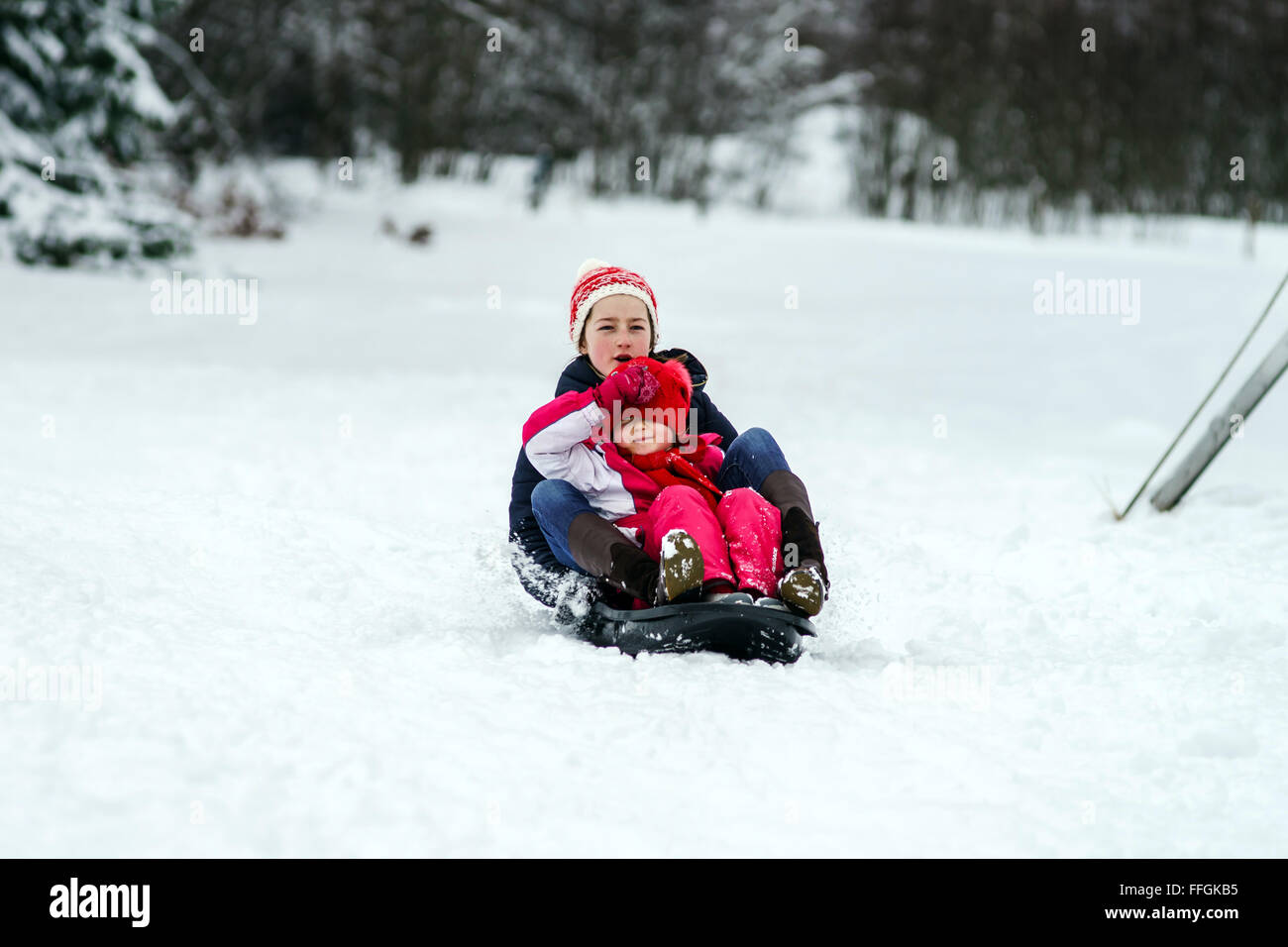 Two sisters riding by sleds winter day, childhood concept Stock Photo ...