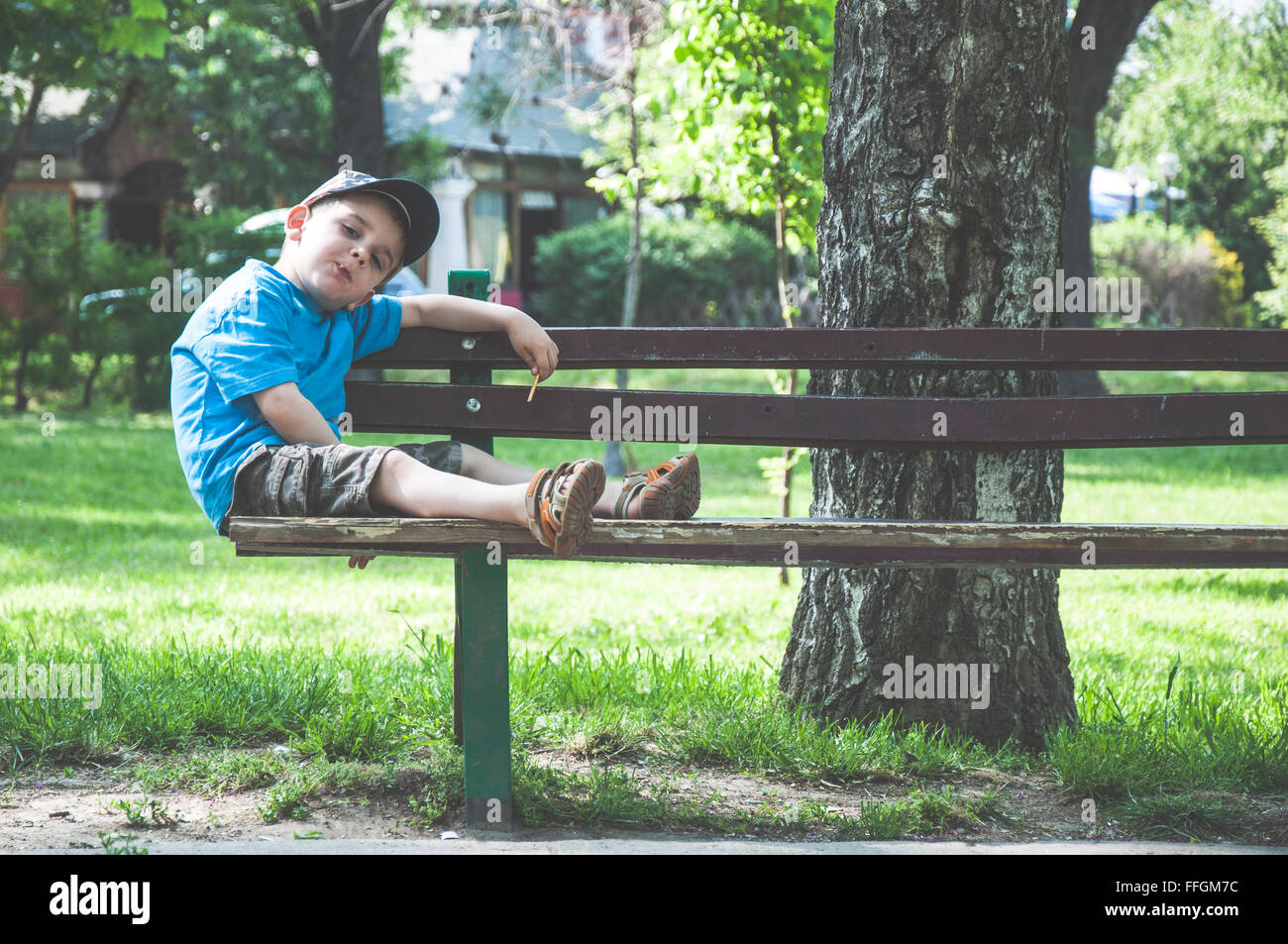 Little boy on a bench in the park Stock Photo - Alamy