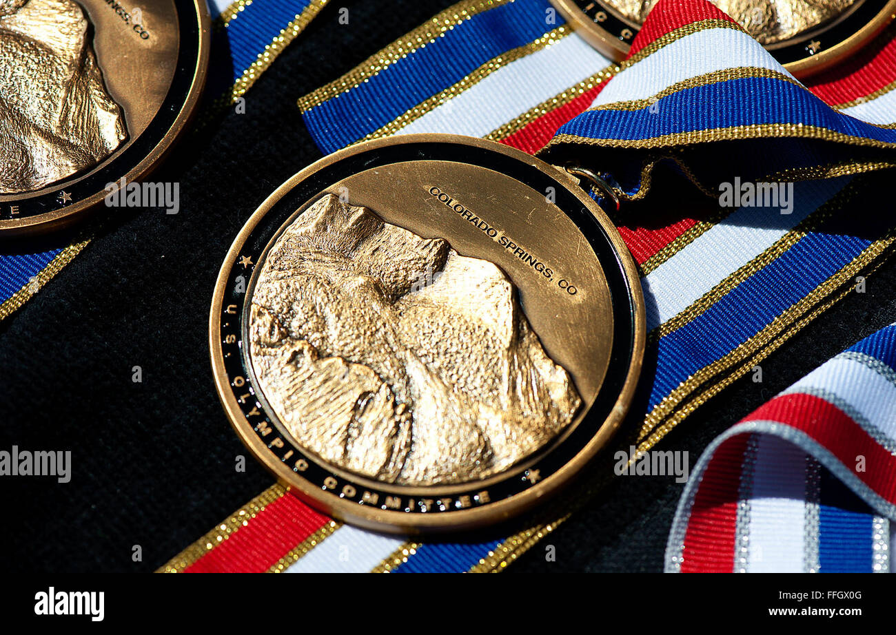 Gold medals are displayed on a table while athletes compete in the ...