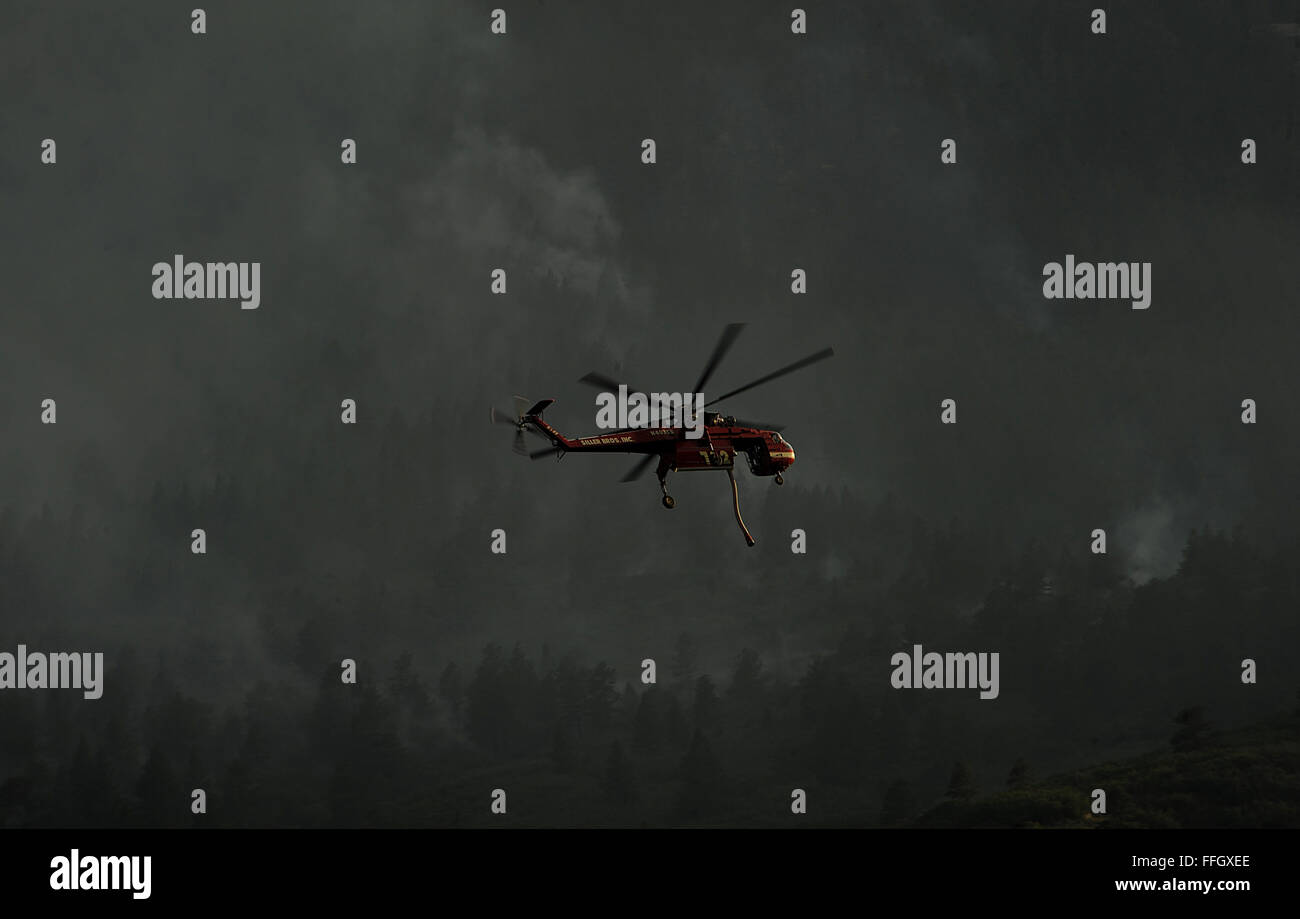 A helicopter prepares to drop water on the fire as firefighters ...