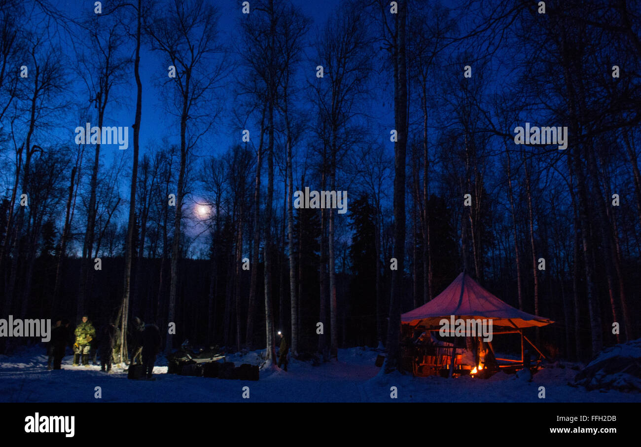 Arctic Survival School students gather around a fire as they learn how ...
