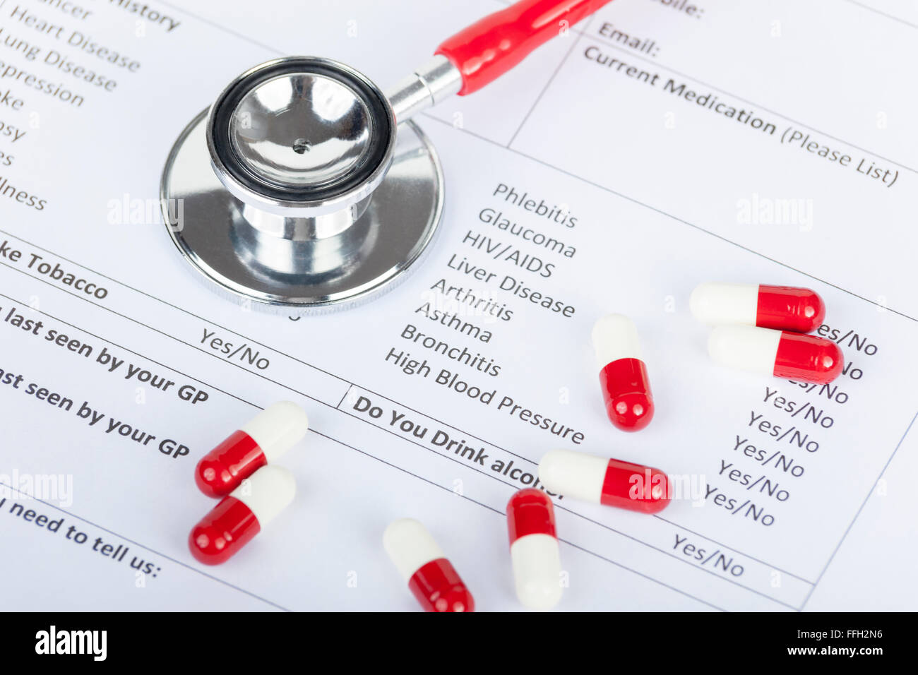 Red ststhoscope and some red and white pill capsules laying on medical ...