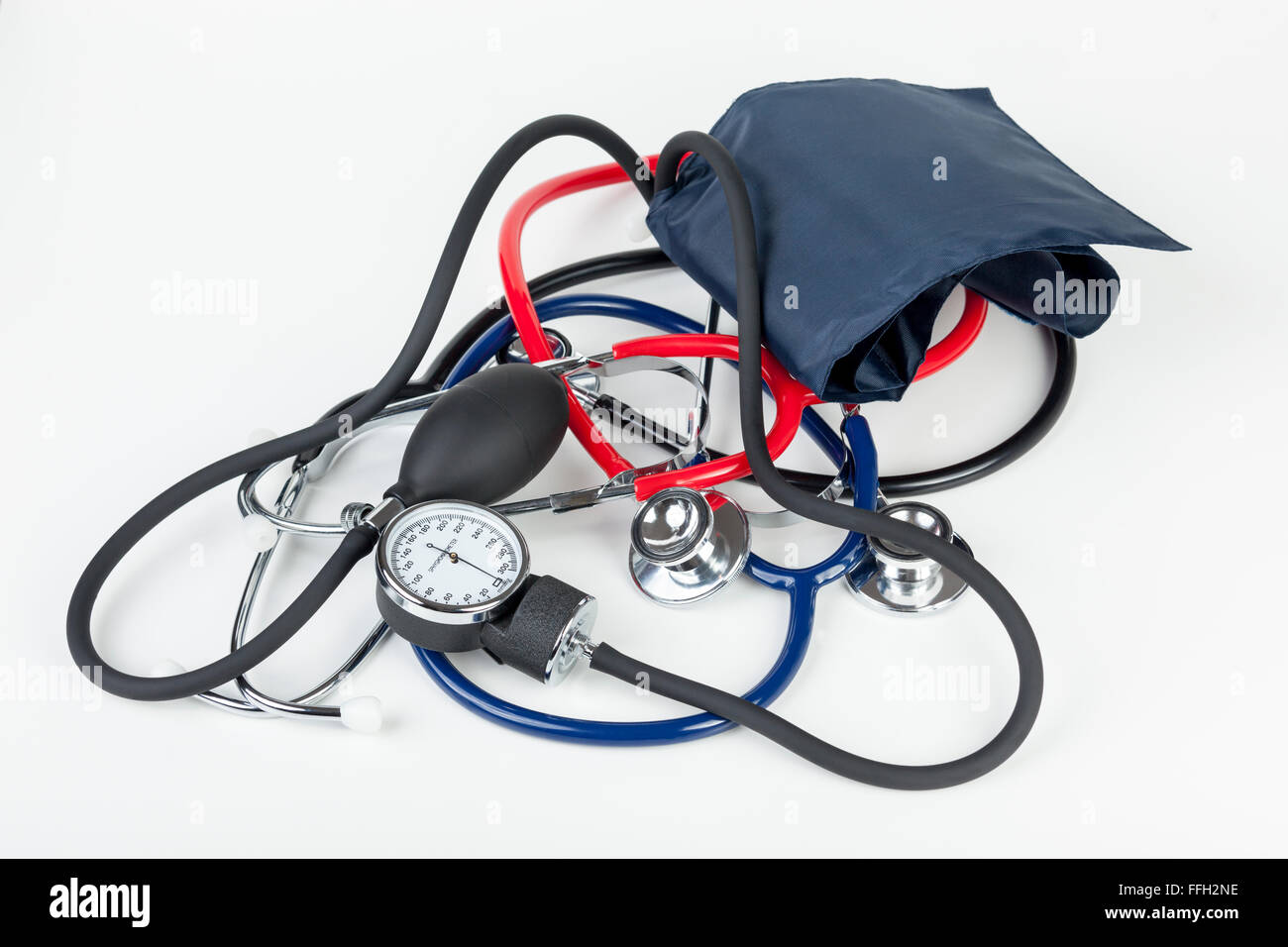 Sphygmomanometer and three stethoscopes laying on a white medical ...