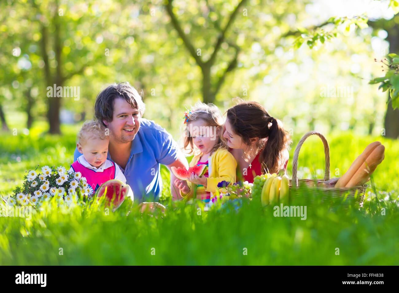 Family with children enjoying picnic in spring garden. Parents and kids ...