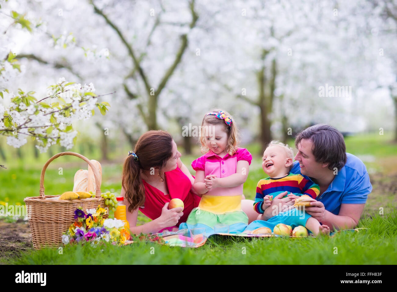 Family with children enjoying picnic in spring garden. Parents and kids ...