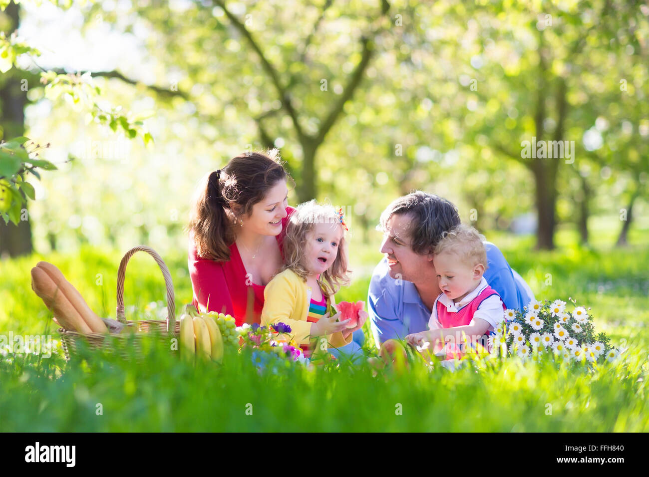 Family with children enjoying picnic in spring garden. Parents and kids ...