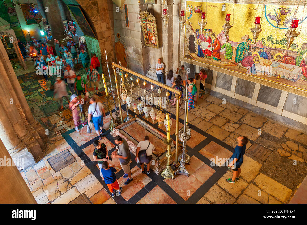 People around Stone of Anointing and mosaic icon on the wall at the ...