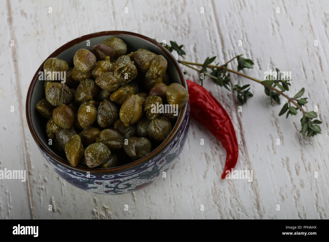 Pickled capers in the bowl on wood background Stock Photo - Alamy