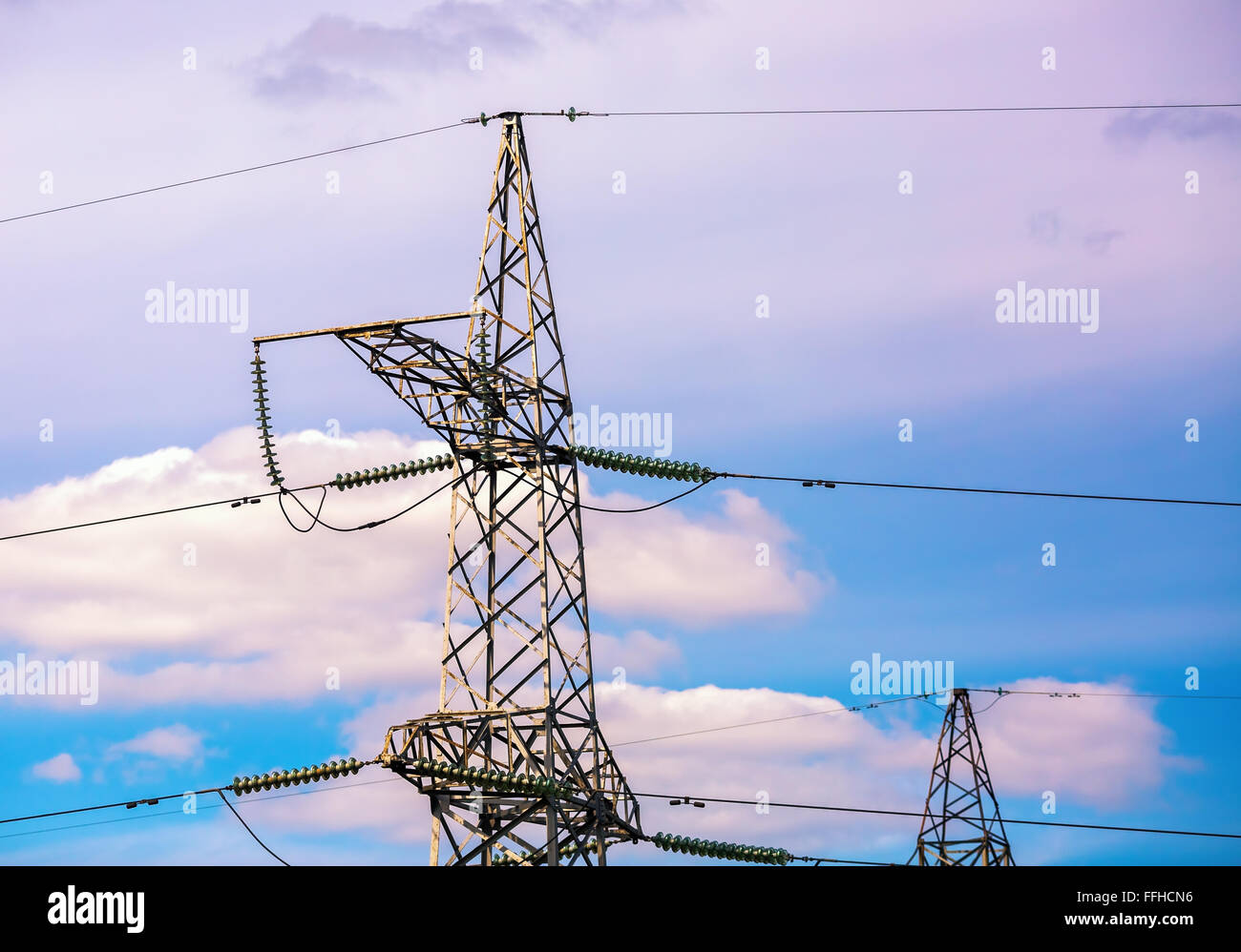 Electric pylon with cables against a bright evening sky. High voltage ...