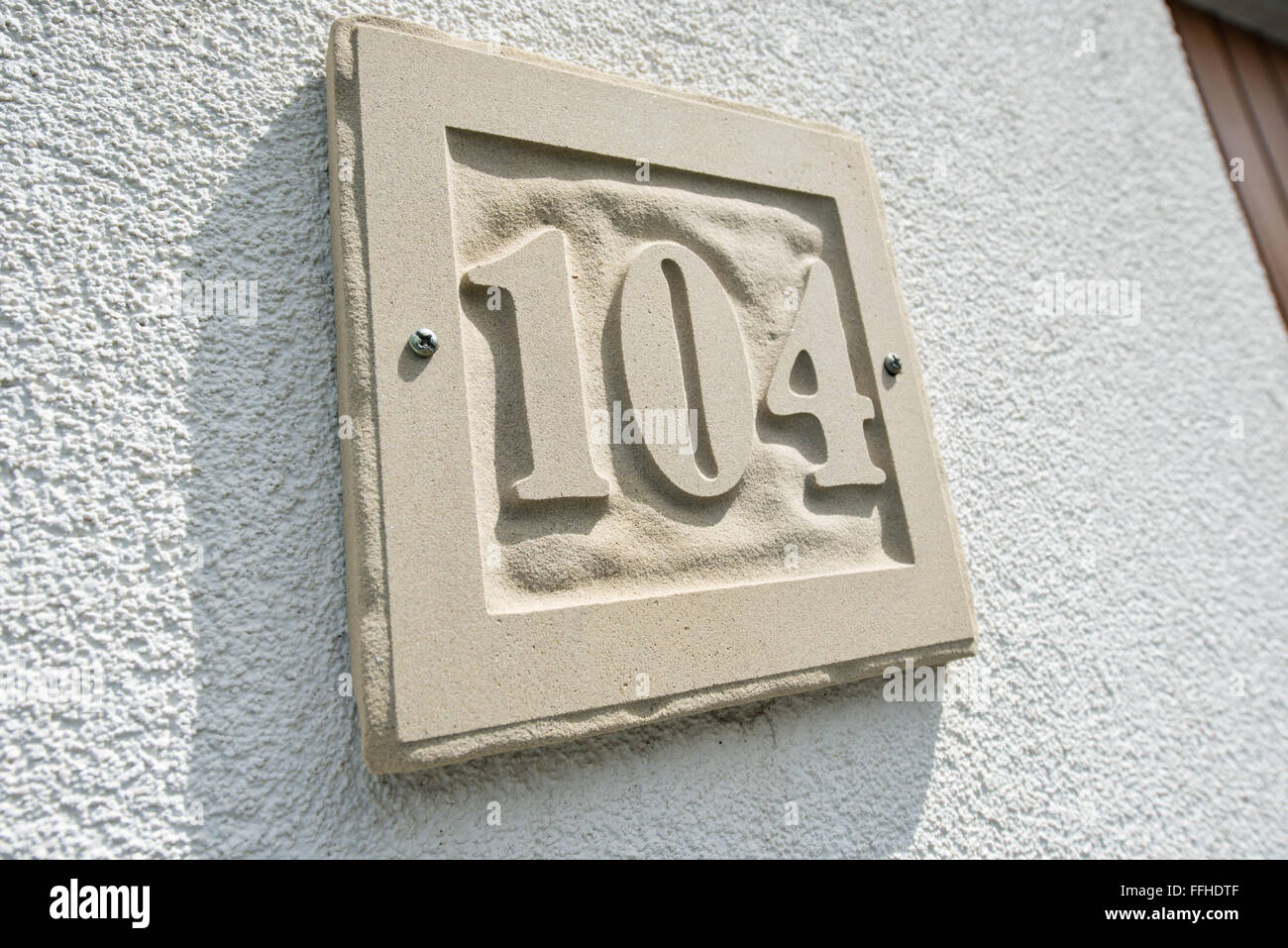 A cat concrete plaque with the number 104 screwed to the stuccoed wall ...