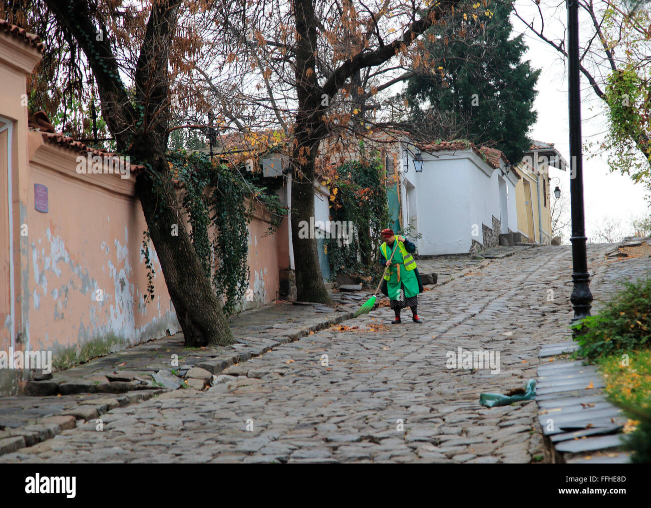 Woman sweeping cobbled street in old town of Plovdiv, Bulgaria, eastern ...