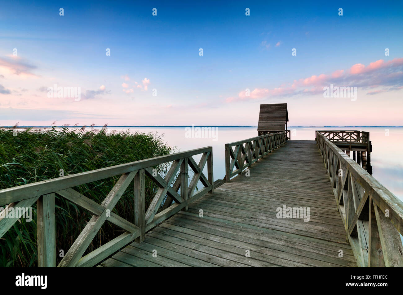 Colorful sunset over calm lake viewed from a wooden bridge Stock Photo ...