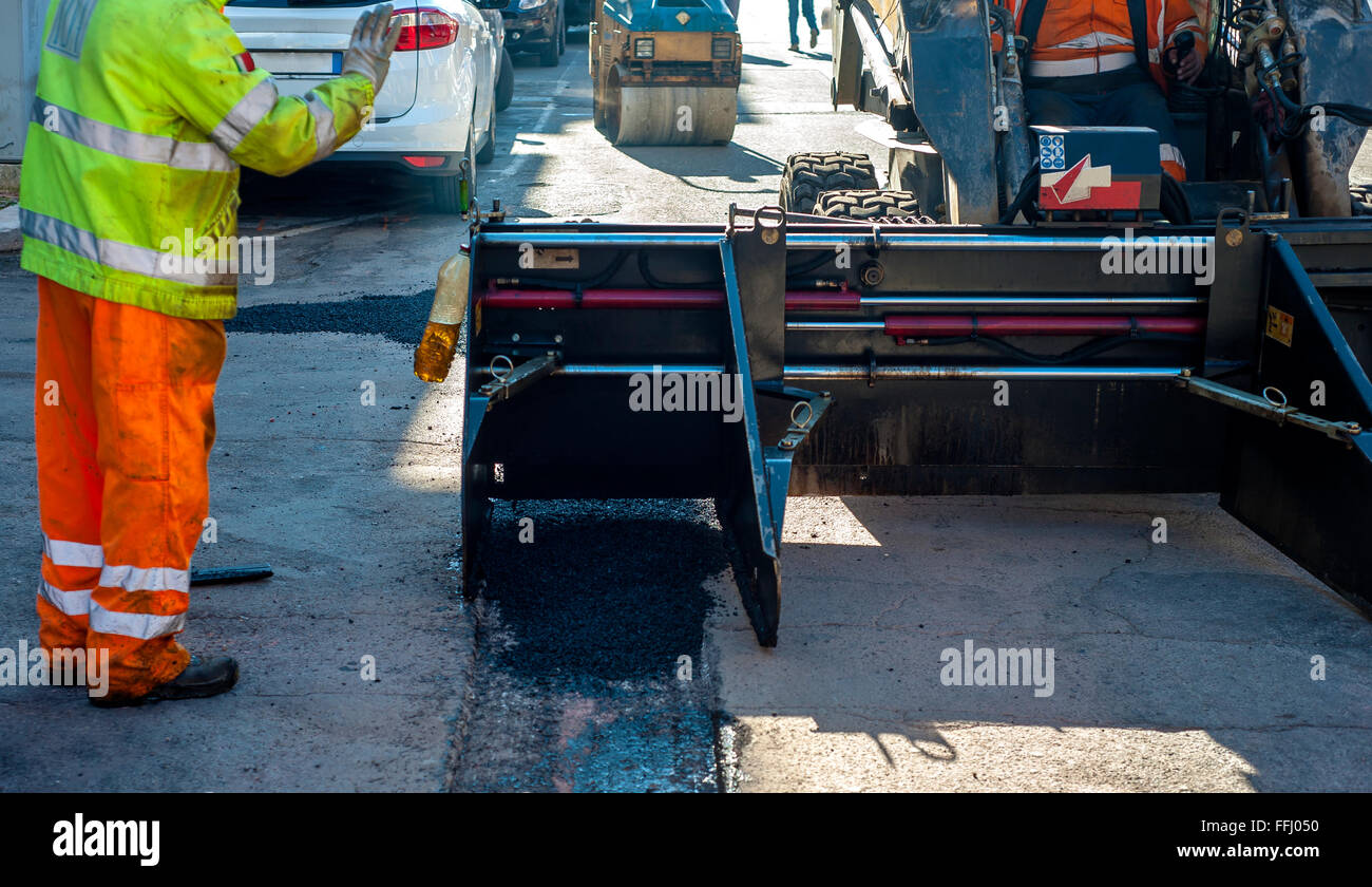 Worker operating asphalt paver machine during road construction and ...