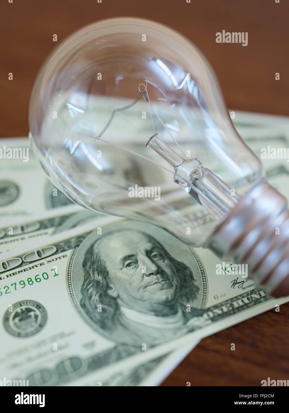 Incandescent light bulb on one hundred dollar bill heap Stock Photo - Alamy