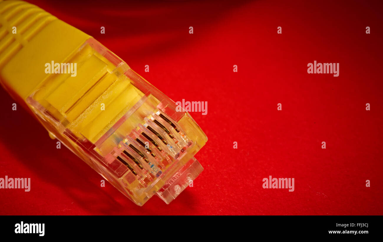 yellow network cable on red background Stock Photo - Alamy