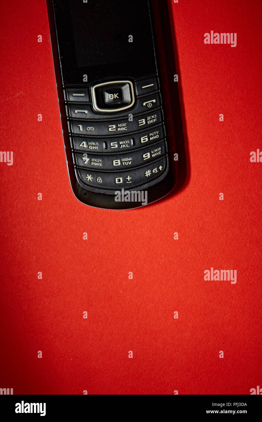 Old black cell phone on the red background Stock Photo - Alamy