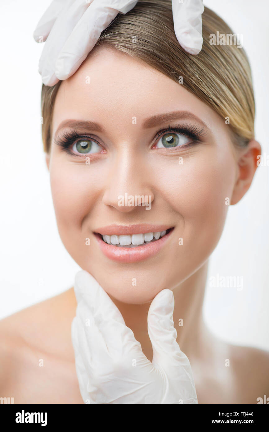 Professional surgeon examining face of pretty woman Stock Photo - Alamy