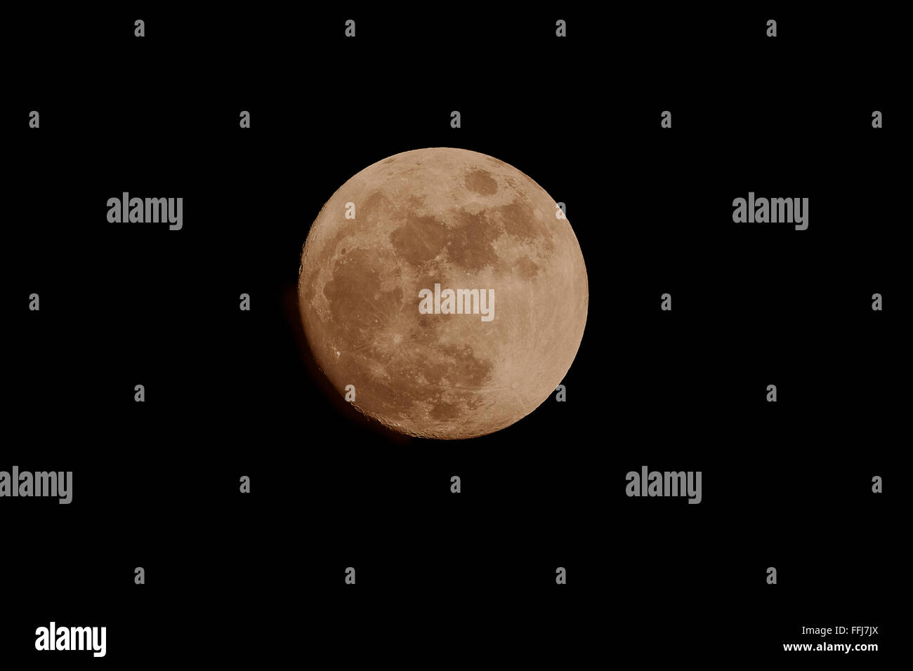 Image of a full amber moon shot during the evening shows orange color ...