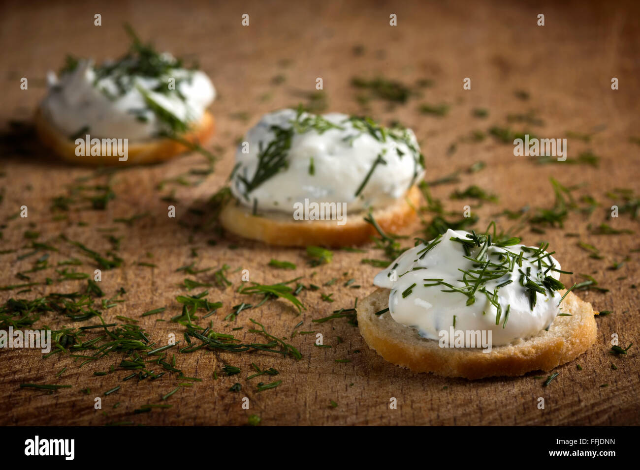 Cracker with cream cheese spread topping and dill over wooden ...