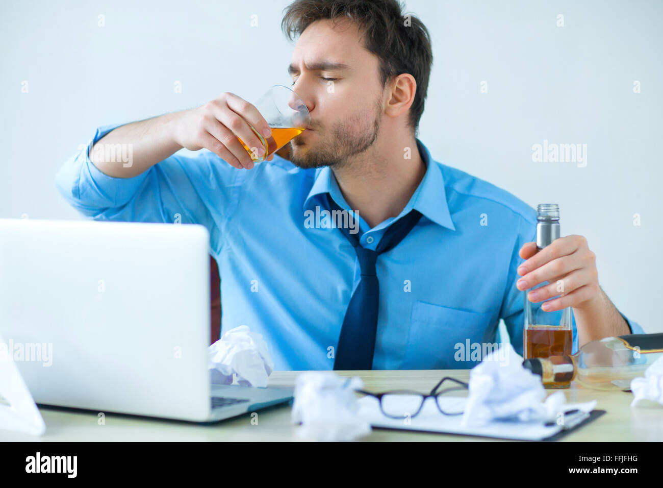 Drunk man drinking alcohol while working Stock Photo - Alamy