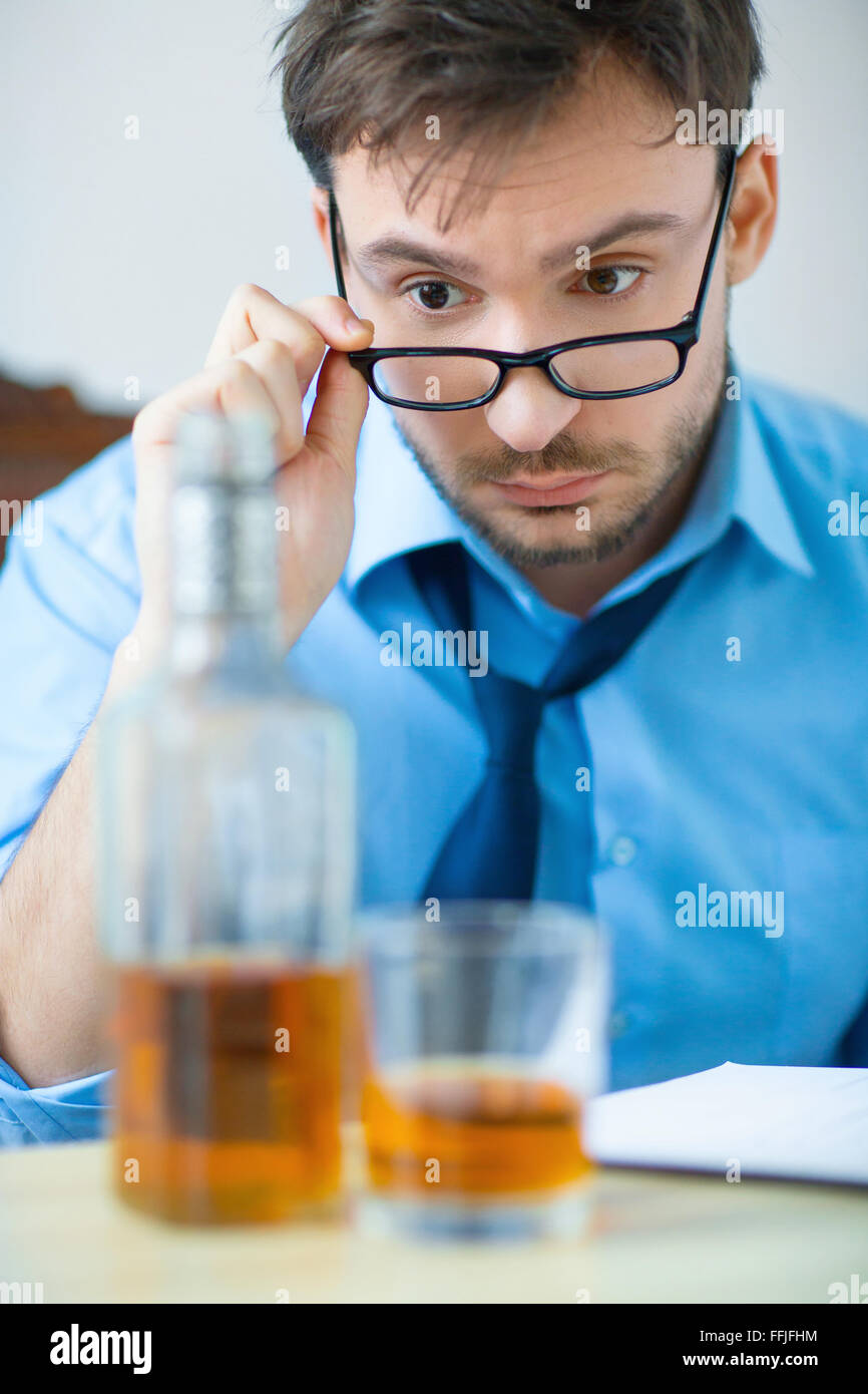 Drunk man drinking alcohol while working Stock Photo - Alamy