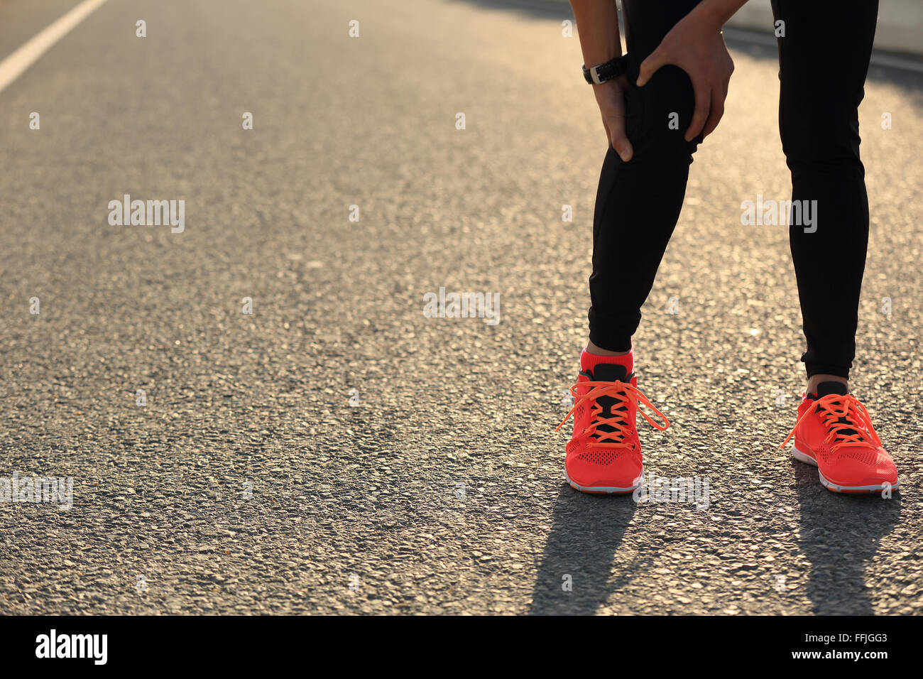 woman runner hold her injured leg on road Stock Photo - Alamy