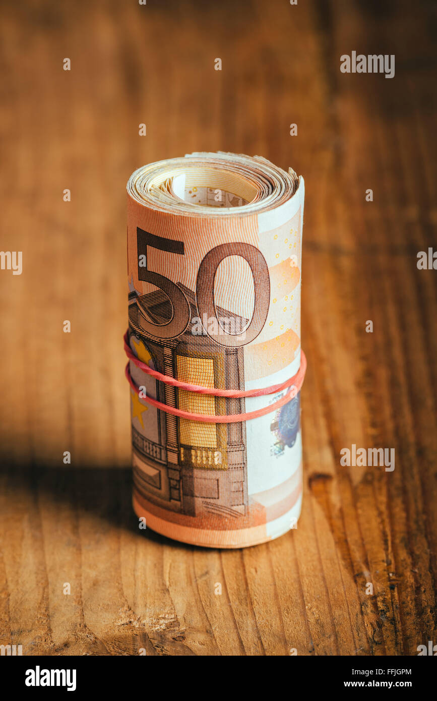 Saving money concept, rolled up cash money with rubber band on wooden ...