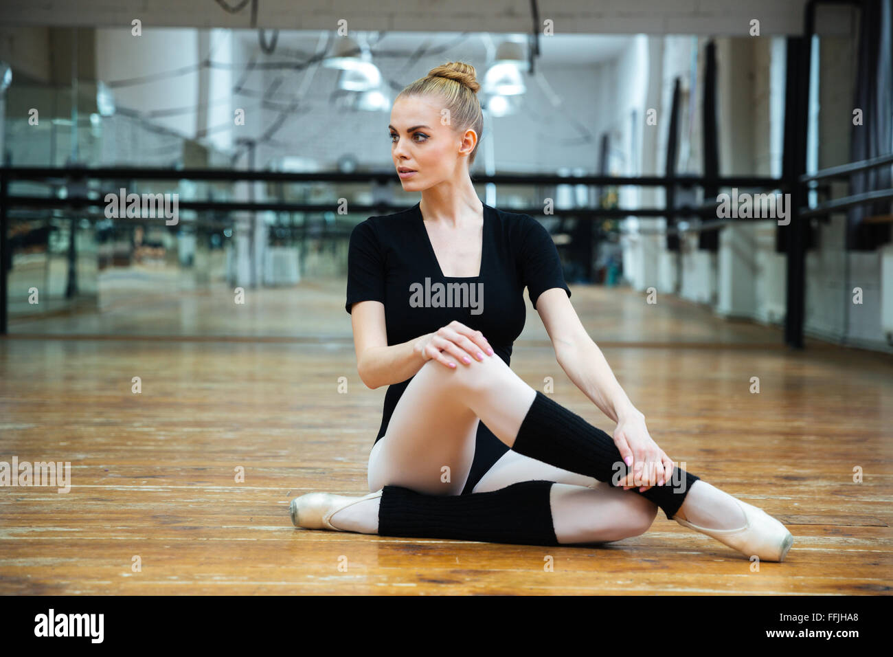 Beautiful ballerina sitting on the floor and looking away in ballet ...