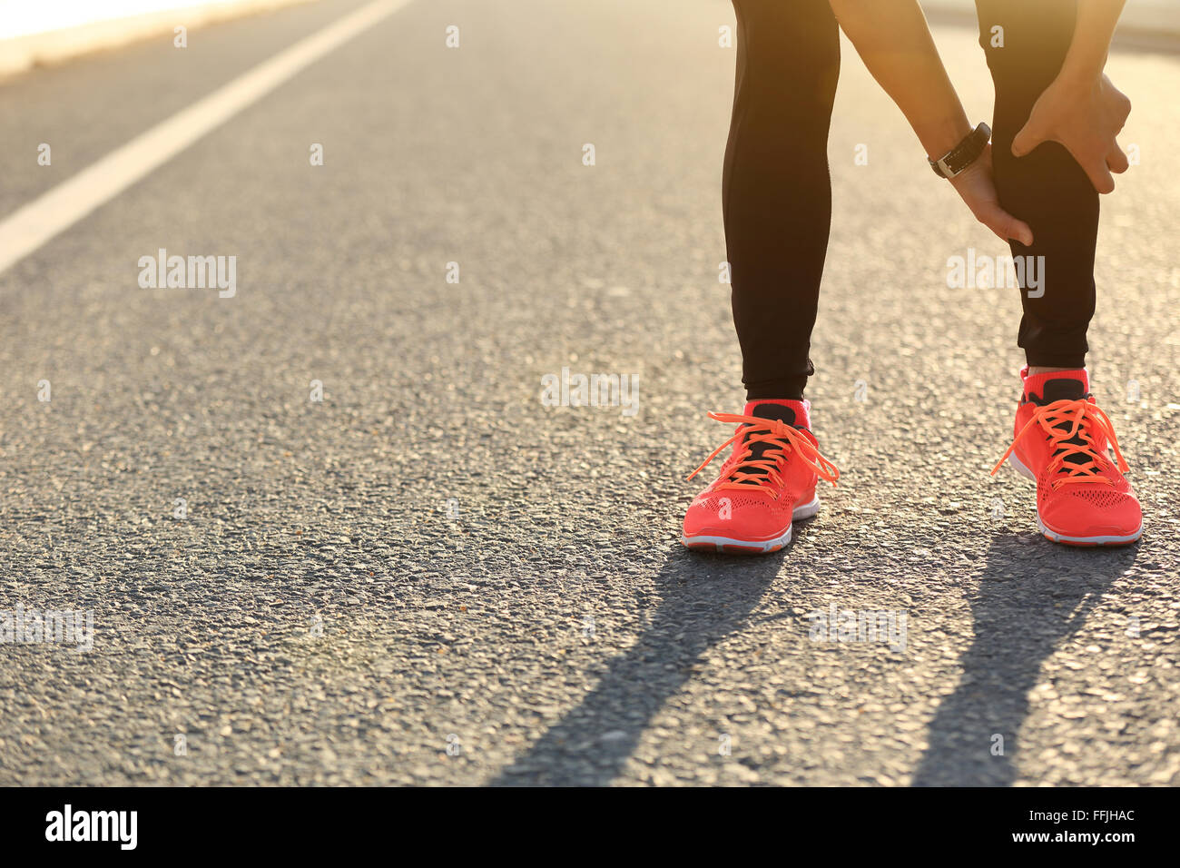 woman runner hold her injured leg on road Stock Photo - Alamy