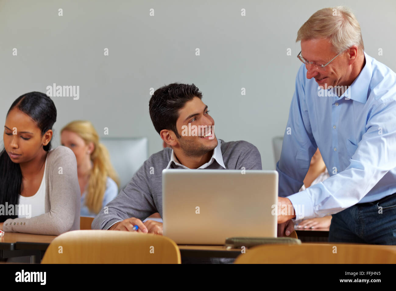 Lecturer talking to student in class at university Stock Photo - Alamy