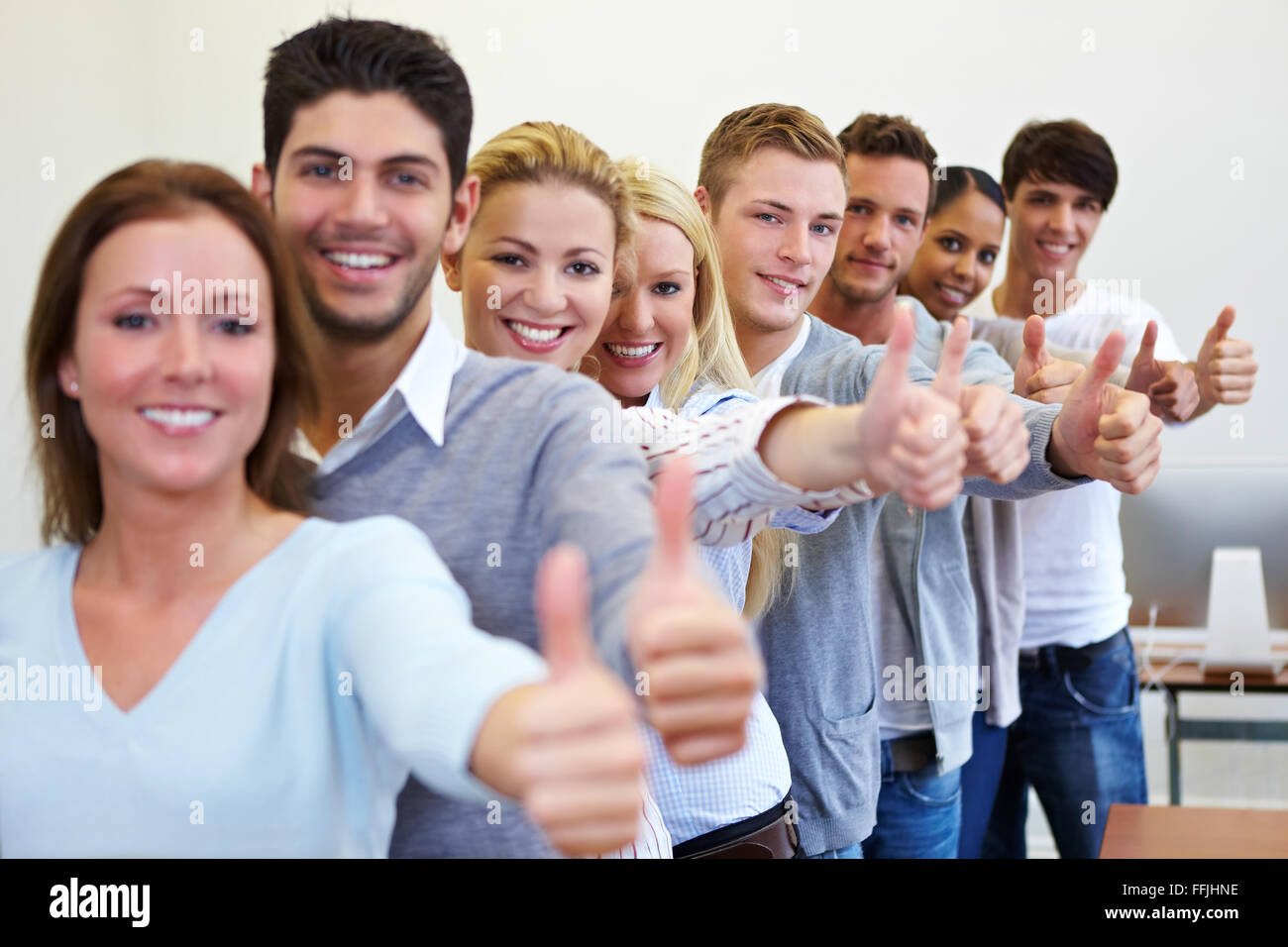 Many happy successful students holding their thumbs up Stock Photo - Alamy